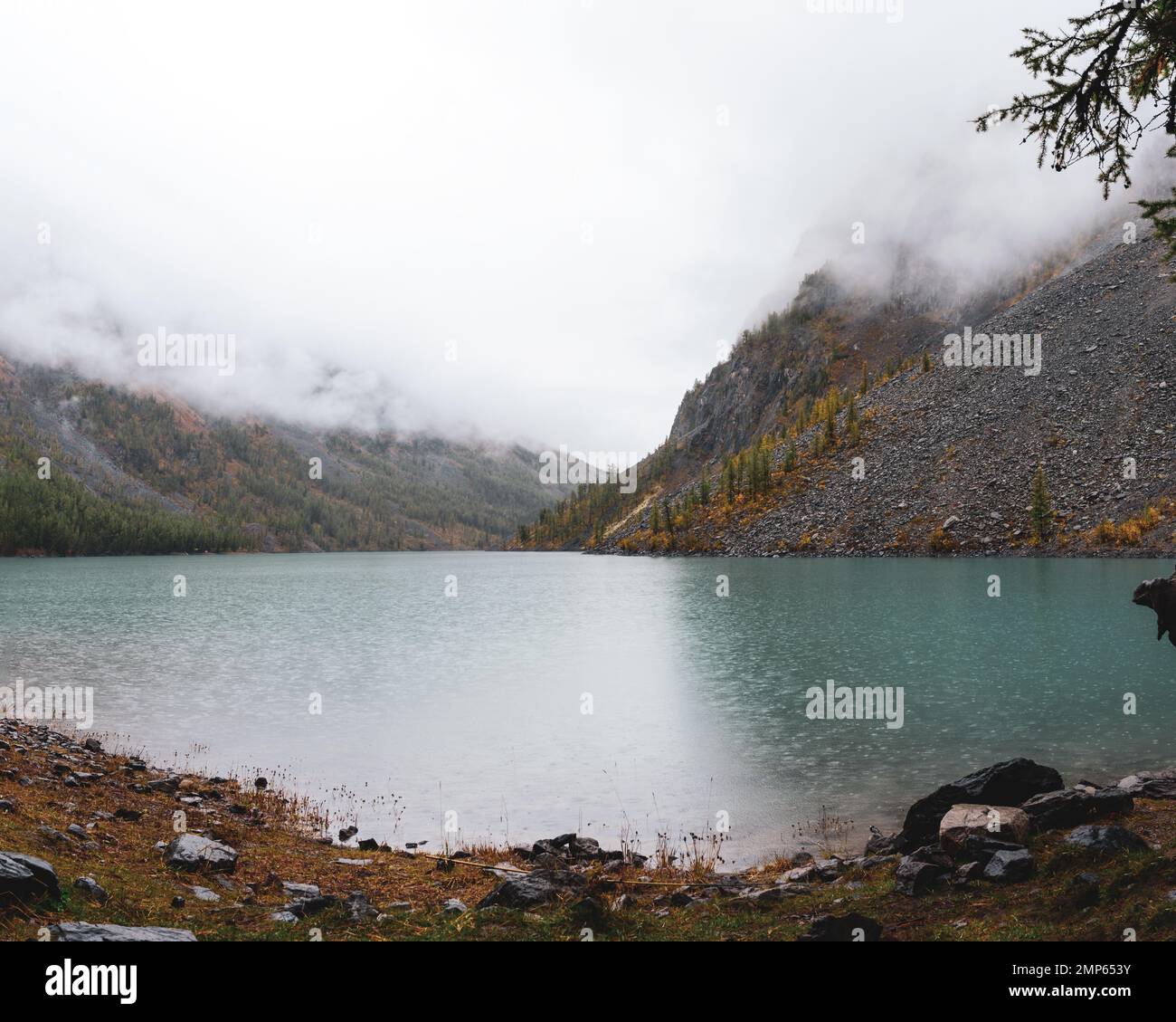 Rain on the alpine turquoise lake Shavlinskoe among the stone rocks ...