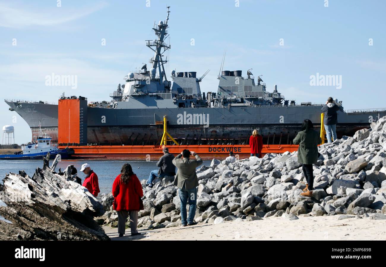 Area residents watch the transport vessel Transshelf carry the damaged ...