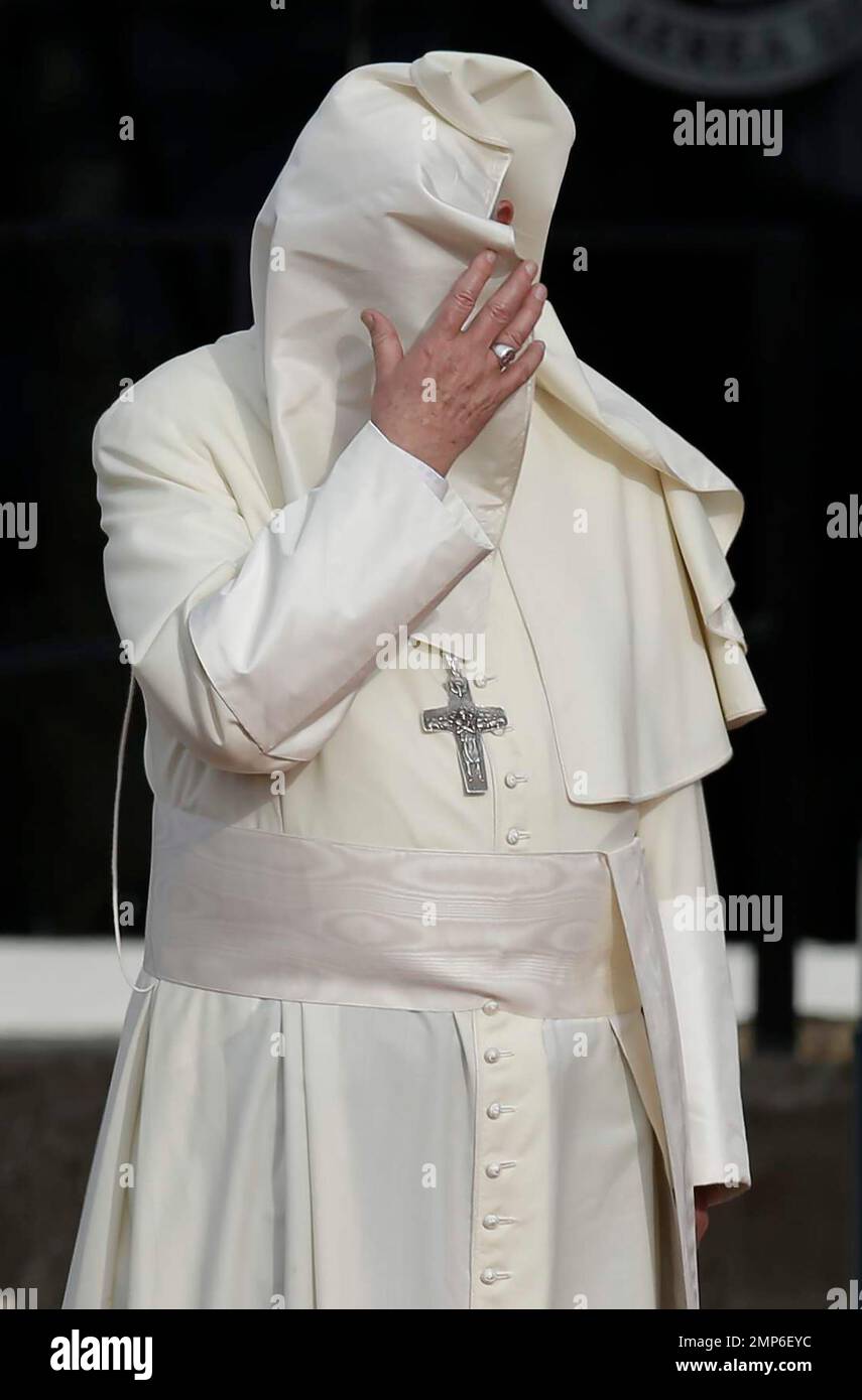 A gust of wind pushes Pope Francis' vestment into his face as he stands ...