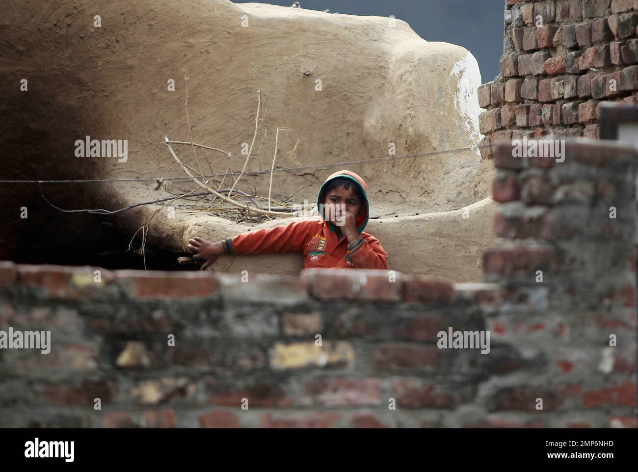 An Indian village boy looks on as relatives wail near the body of ...