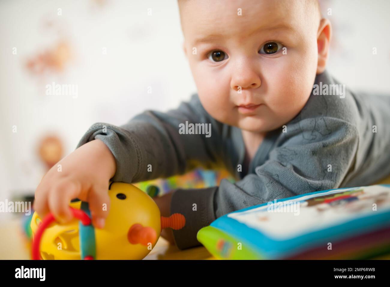 Portrait of cute baby boy playing with colorful toys at home. Close-up ...