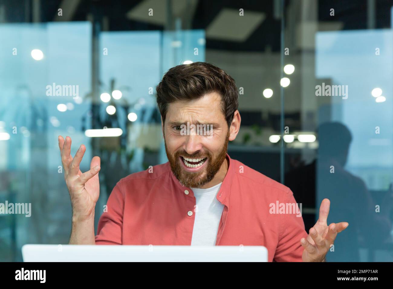 Close up photo. An angry young man in a red shirt is sitting in the ...