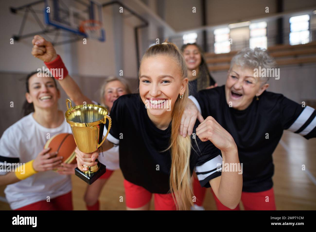 Group of young and old women, basketball team players, in gym with ...