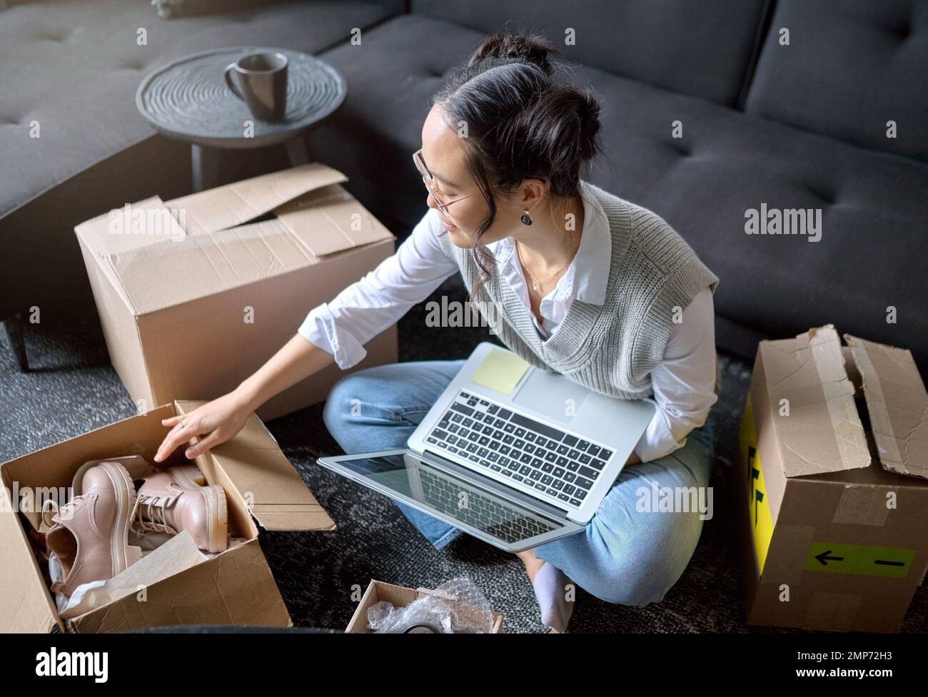 Laptop, real estate and woman moving into new home while unboxing boxes ...