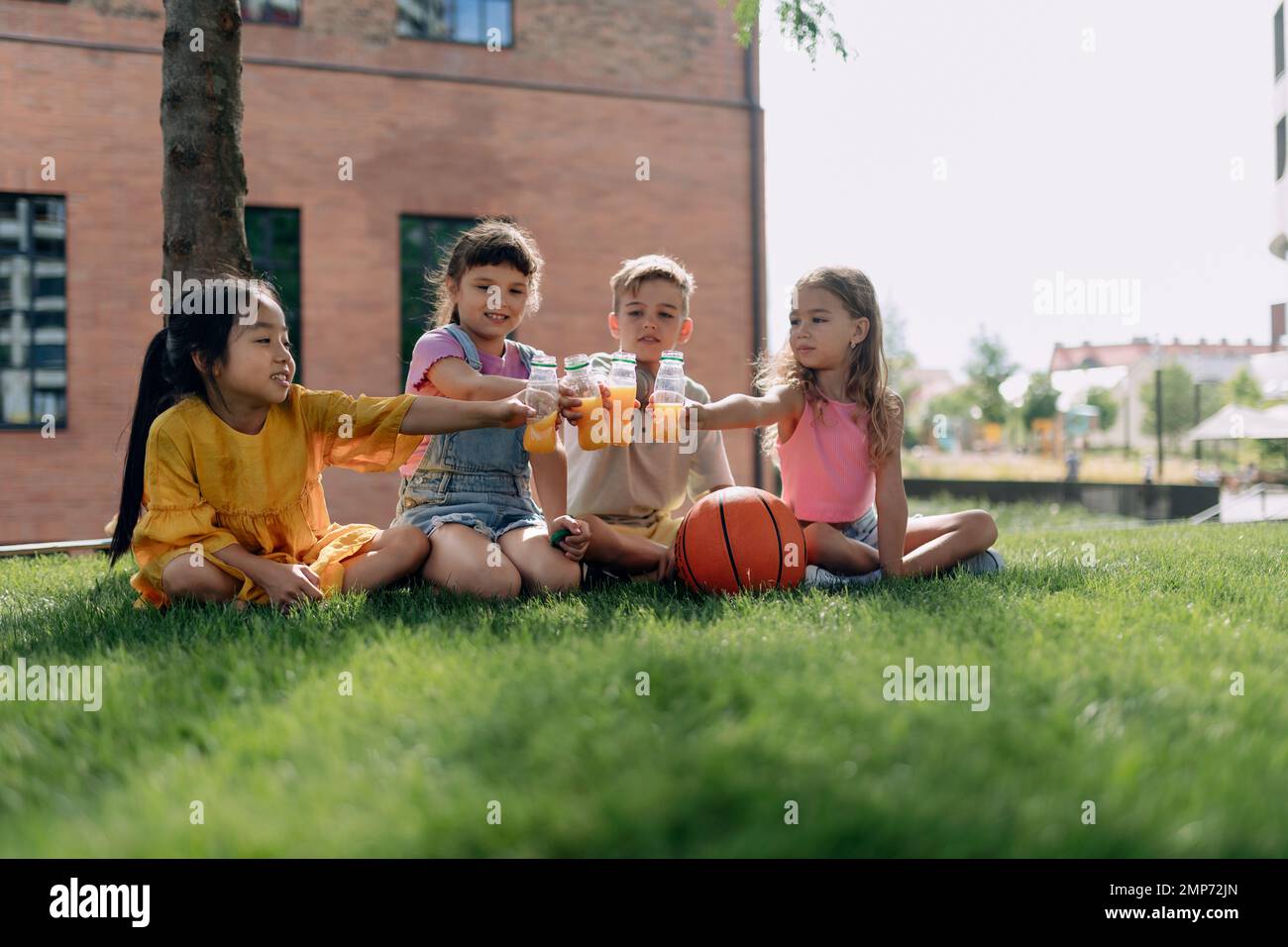 Happy kids playing and talking together in city park, during summer day ...
