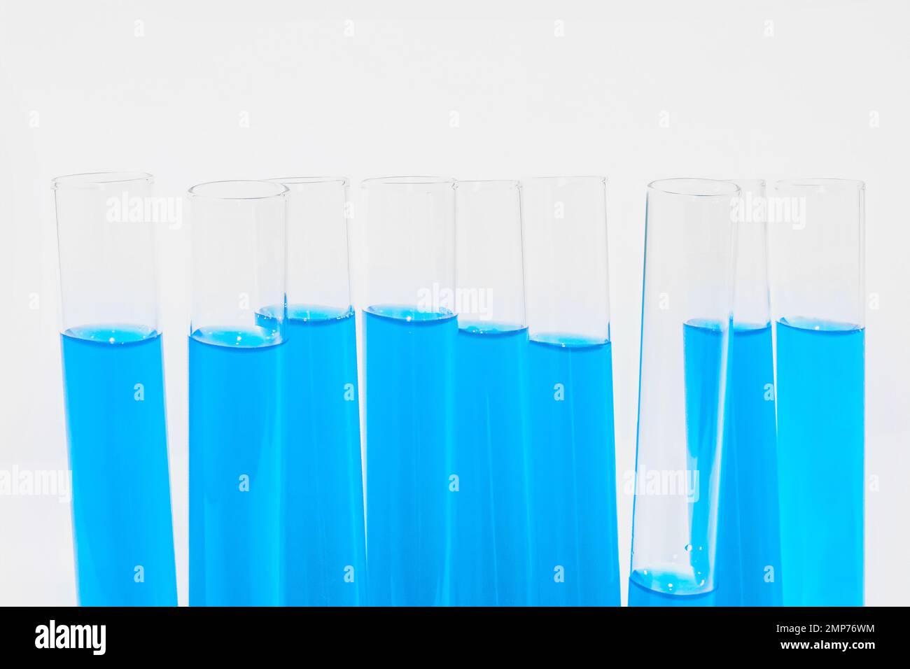 Transparent glass test tubes on a white background, blue liquid ...