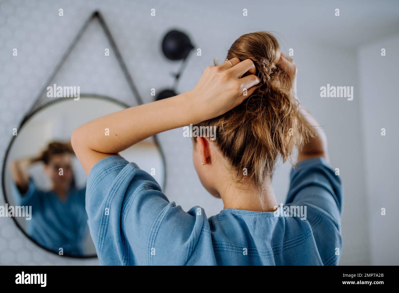 Young woman taking care of her hair, morning beauty routine concept ...