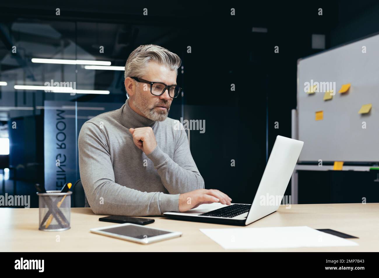 Concentrated senior gray-haired male designer, engineer, architect in ...