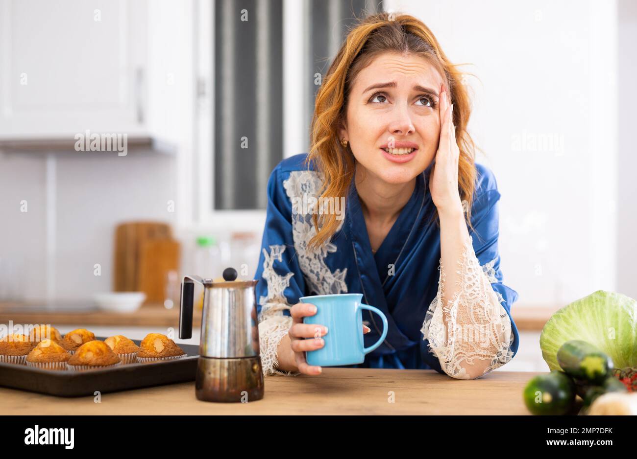 Sleepy Woman In Housecoat Drinking Morning Coffee In Kitchen Stock
