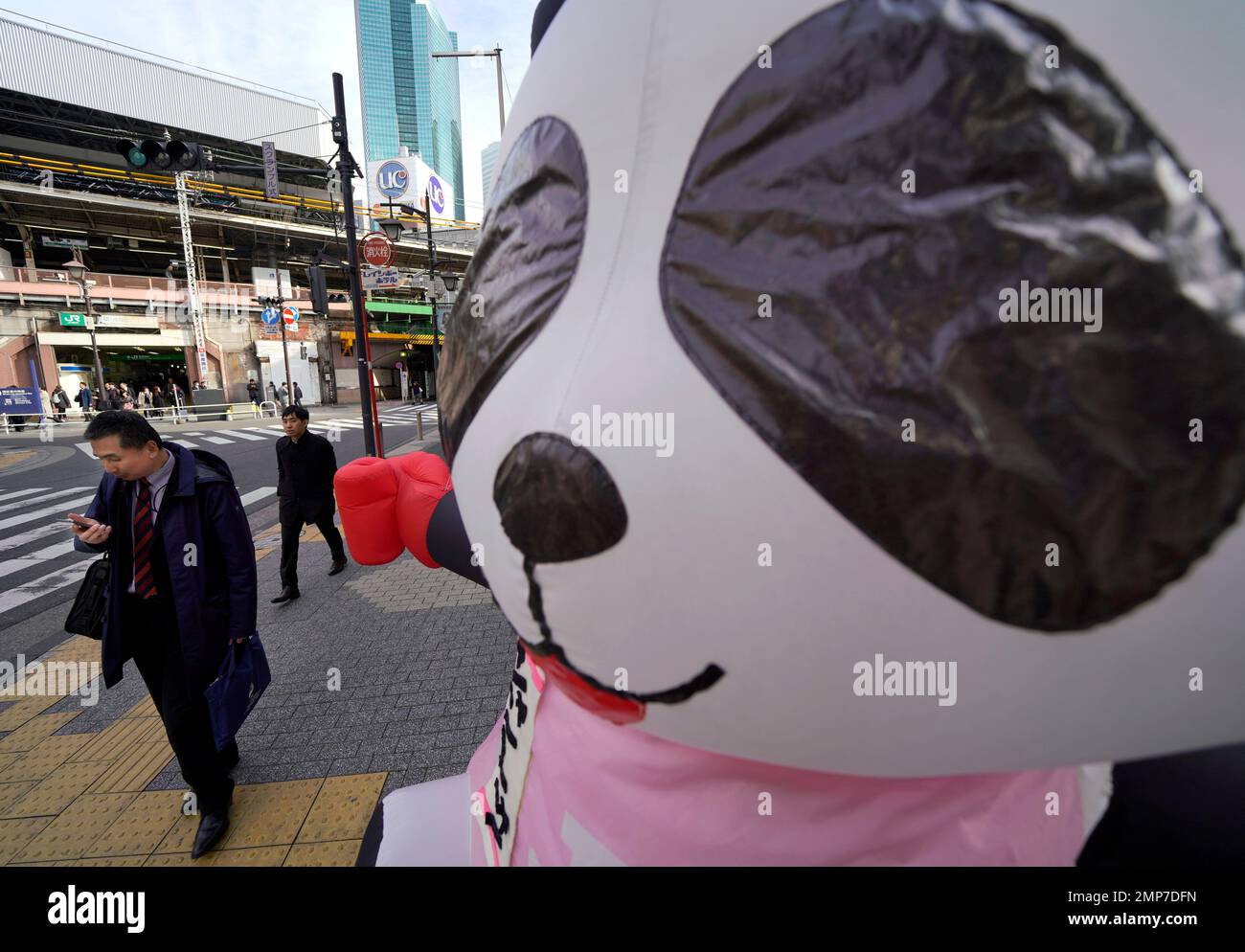 Men walk pass a giant panda balloon in Tokyo, Tuesday, Jan. 16, 2018 ...