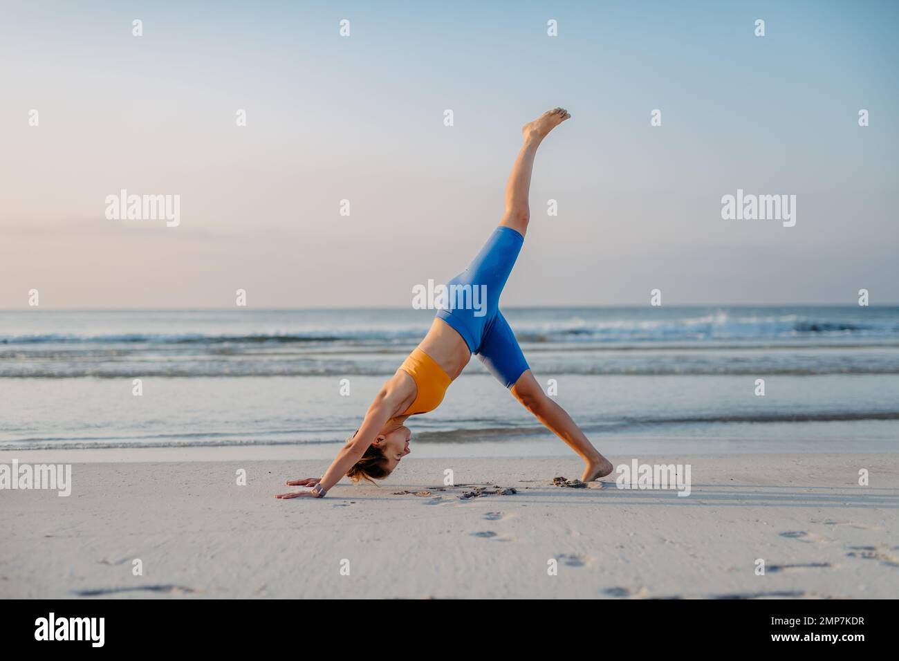 Young woman taking exercises at beach, morning routine and healthy ...