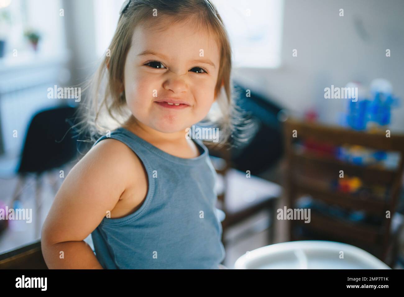 Funny baby girl looking and grimacing at the camera while waiting for ...