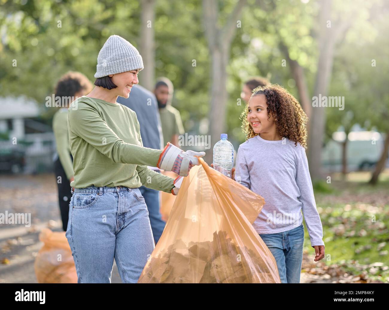 Volunteer, child and woman cleaning plastic in park with garbage bag ...