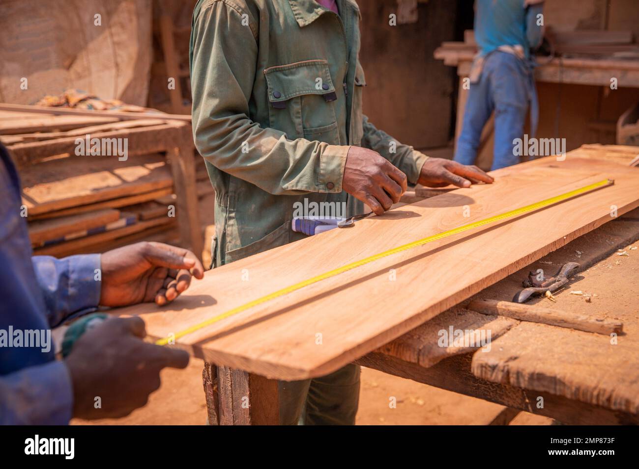 Close-up of carpenters' hands taking measurements of a wooden plank ...