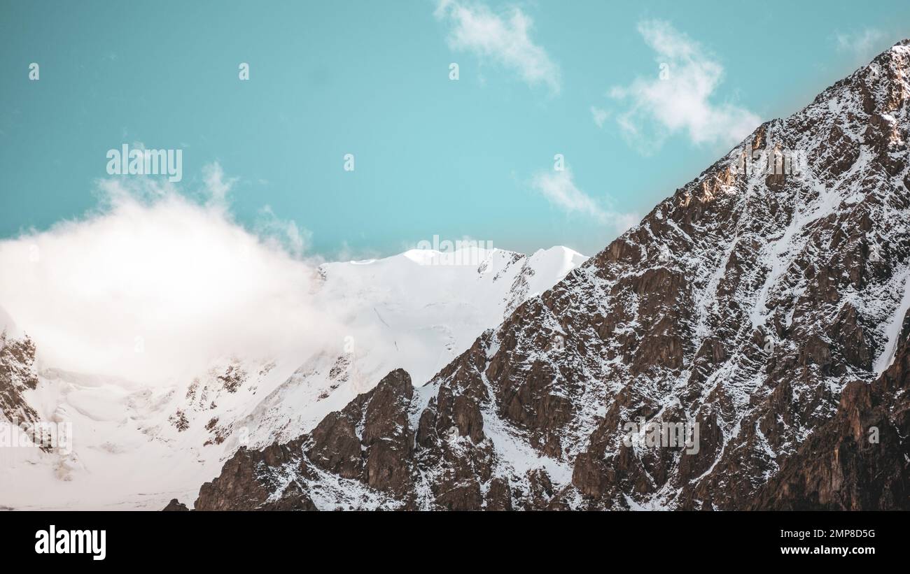 Clouds cover the tops of high mountains with fog with snow and glaciers ...
