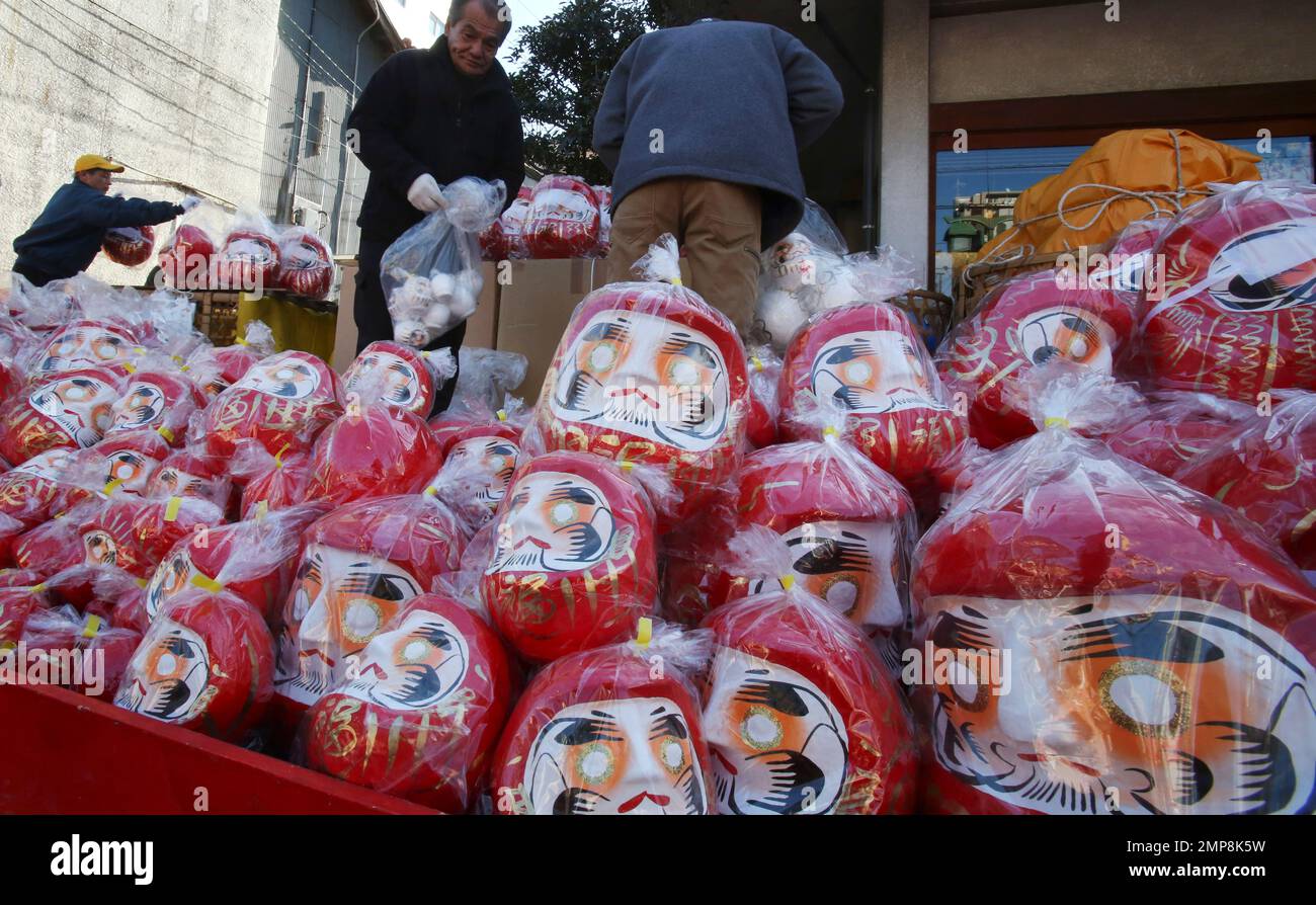 A vendor sells red "Daruma" dolls, a popular talisman of good luck ...