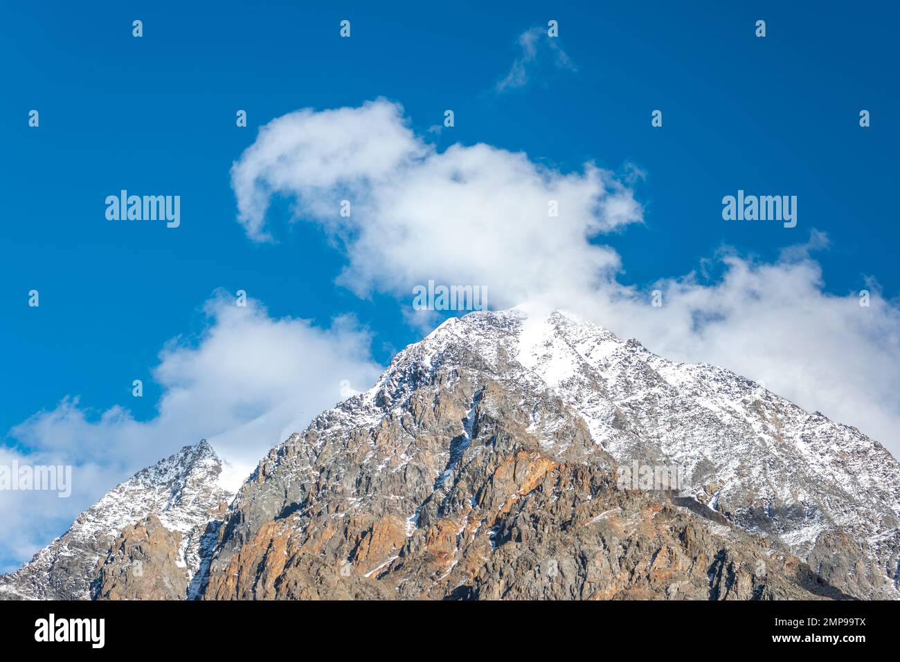 The top of a triangular mountain is covered with snow against the ...