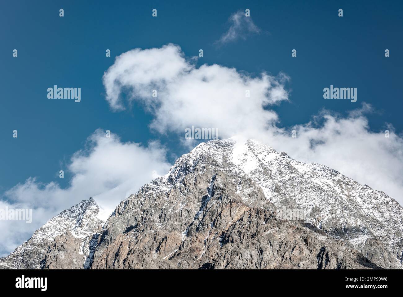 The top of a triangular mountain is covered with snow against the ...