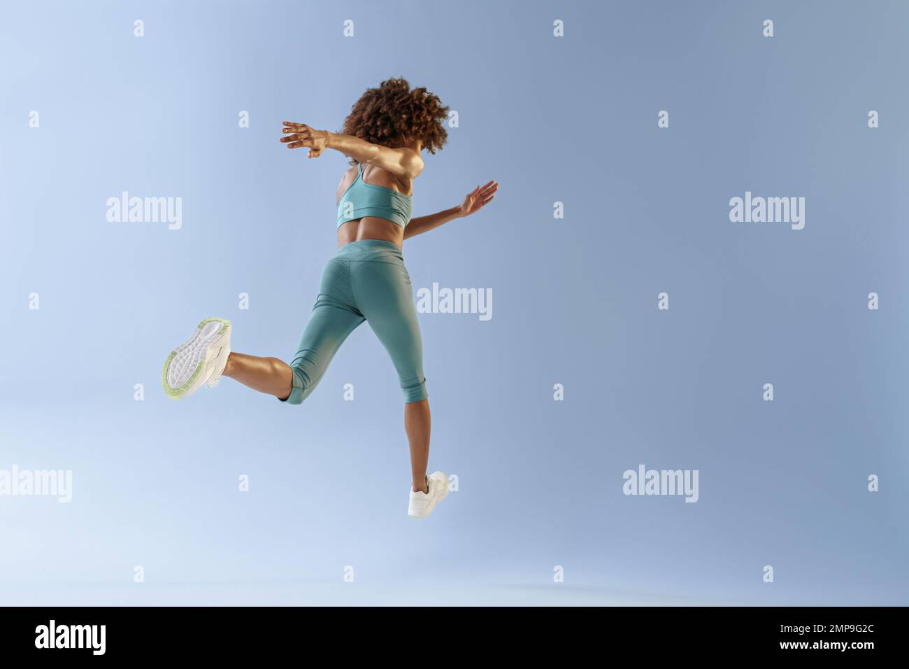 Back view of sporty woman running in Mid-Air exercising during cardio ...