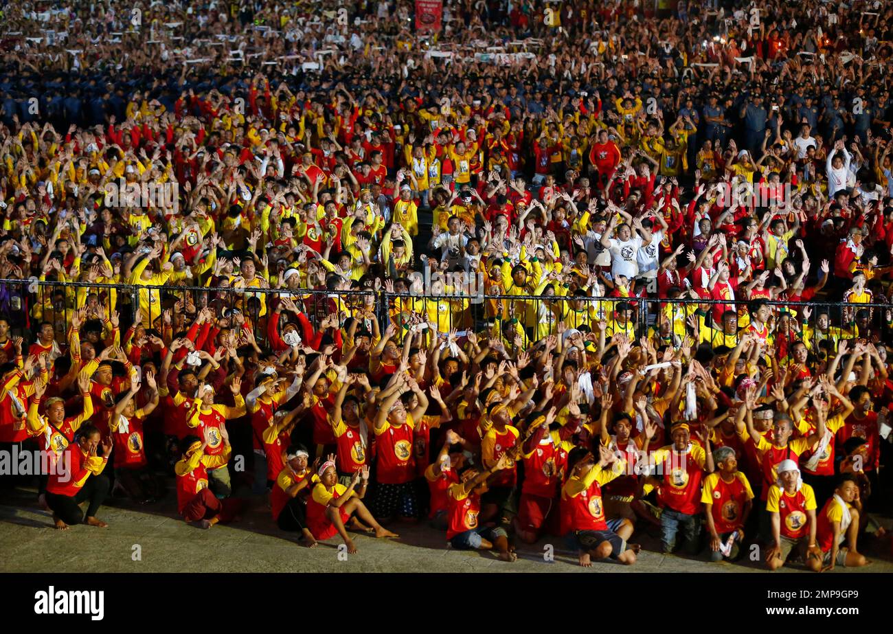 Roman Catholic devotees raise their hands in prayer prior to a raucous ...