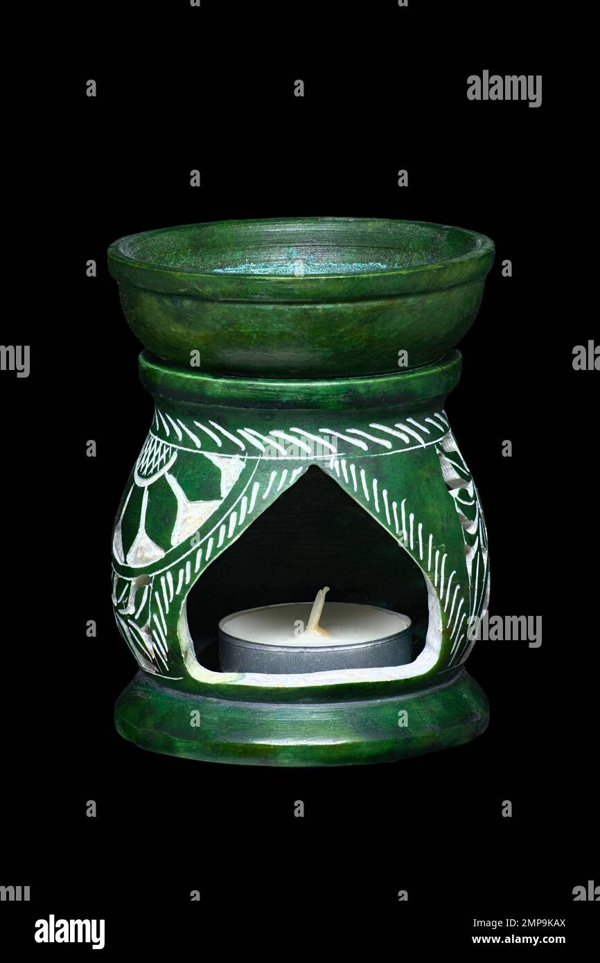 Image of a green ceramic aroma lamp with candles on a black background ...