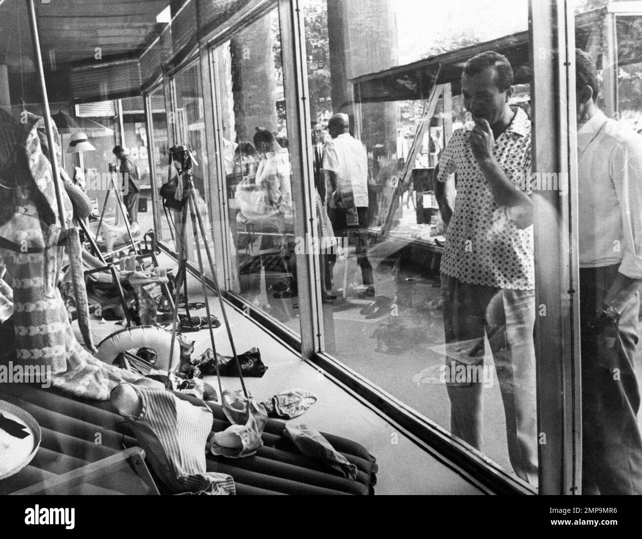 A man looks in the window of a store displaying summer beach goods and ...