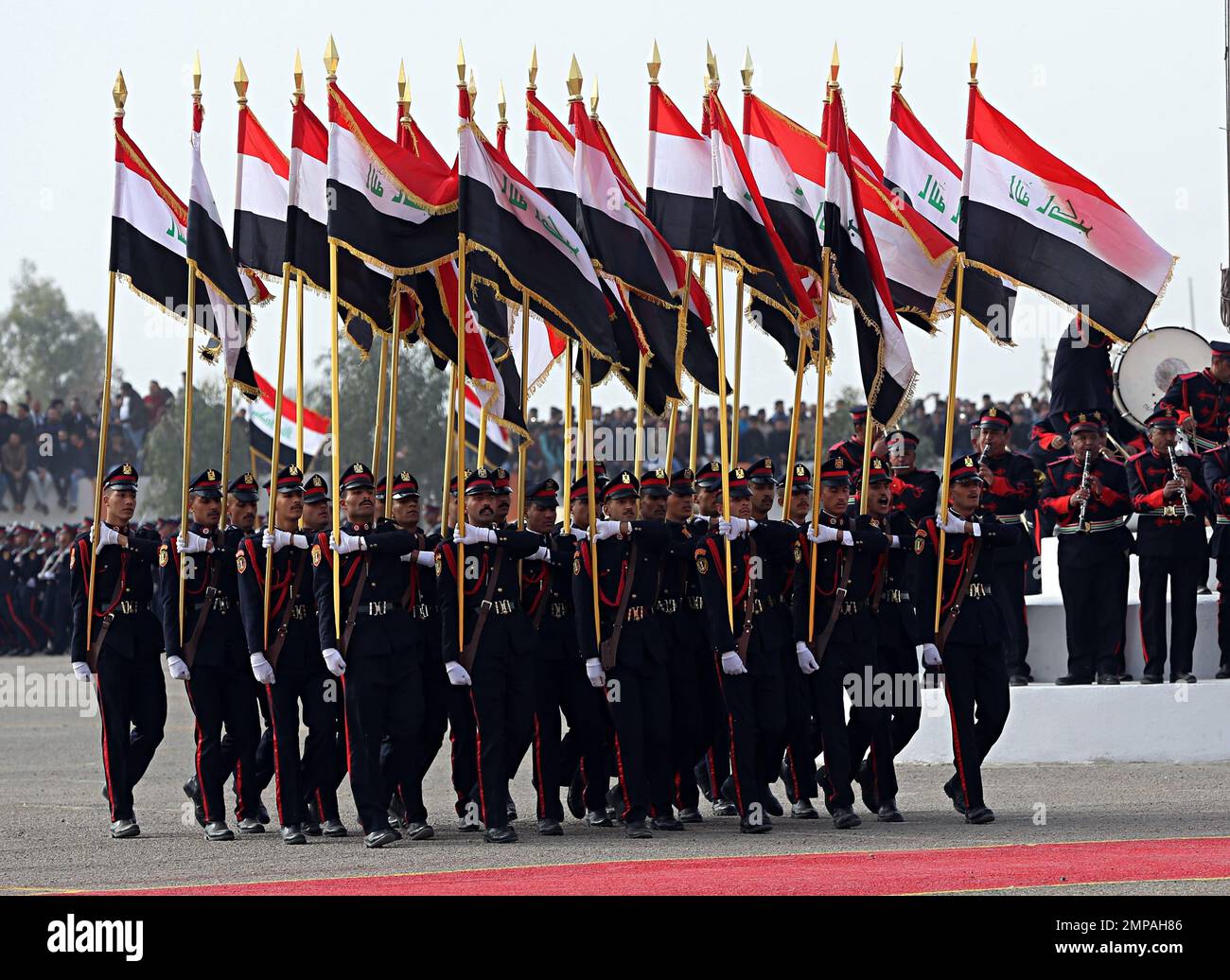 Newly graduated Iraqi Army officers march with national flags during ...