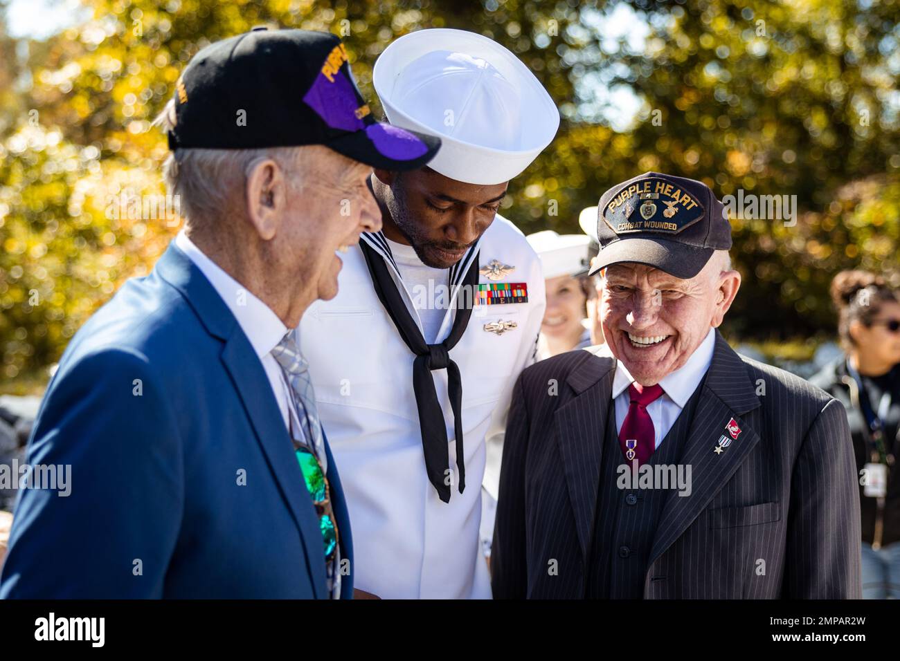 A U.S. Navy sailor, center, poses for a photo with Ret. HM3 John ...