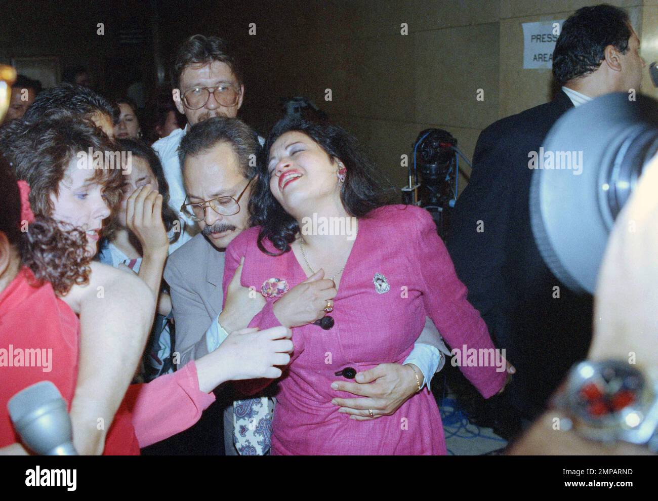 Santiago Rodriguez, center, holds his wife, Evelyn, as she faints ...