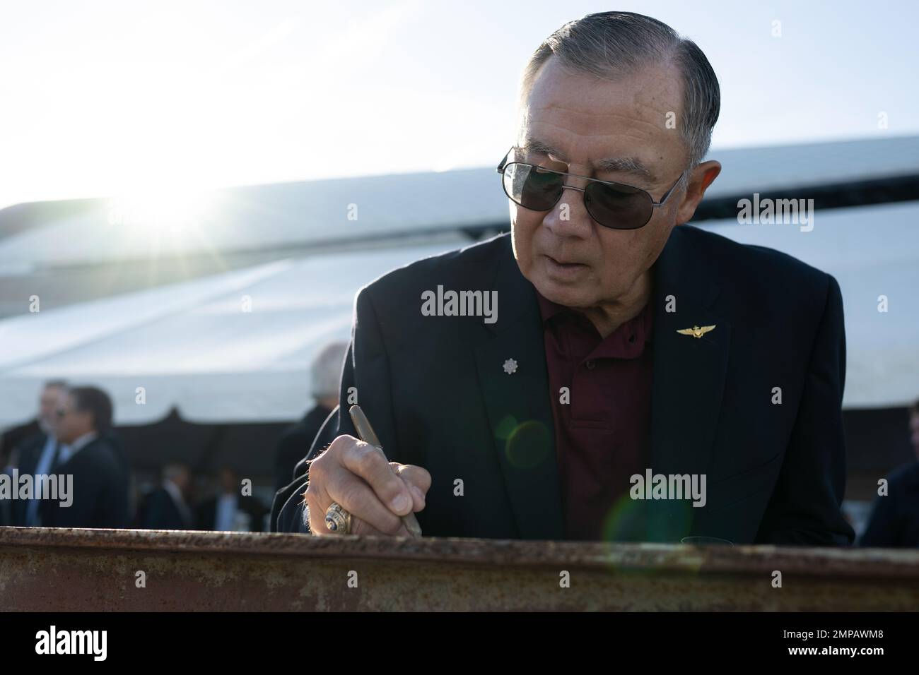 An alumnus of the Coast Guard Academy signs a symbolic steel beam that ...