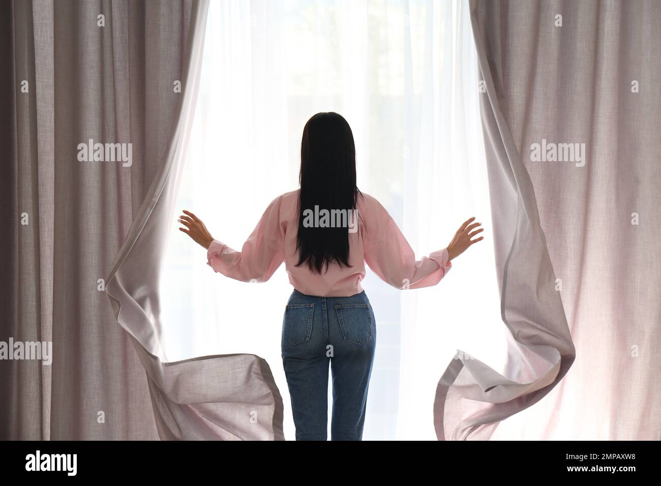 Woman opening window curtains at home in morning, back view Stock Photo ...