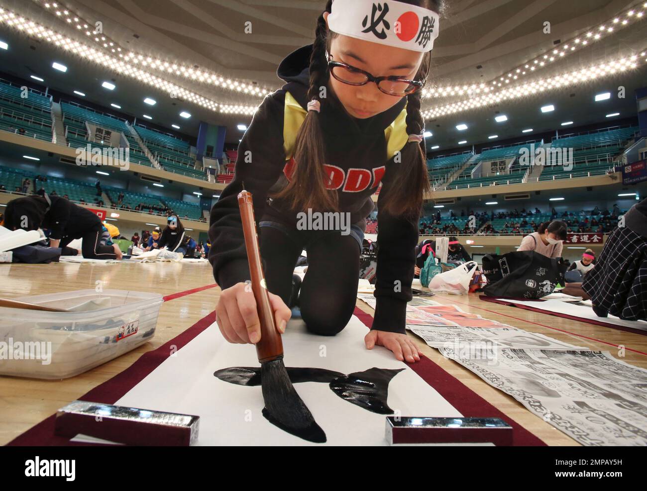 A young participant writes traditional Japanese calligraphy during the ...