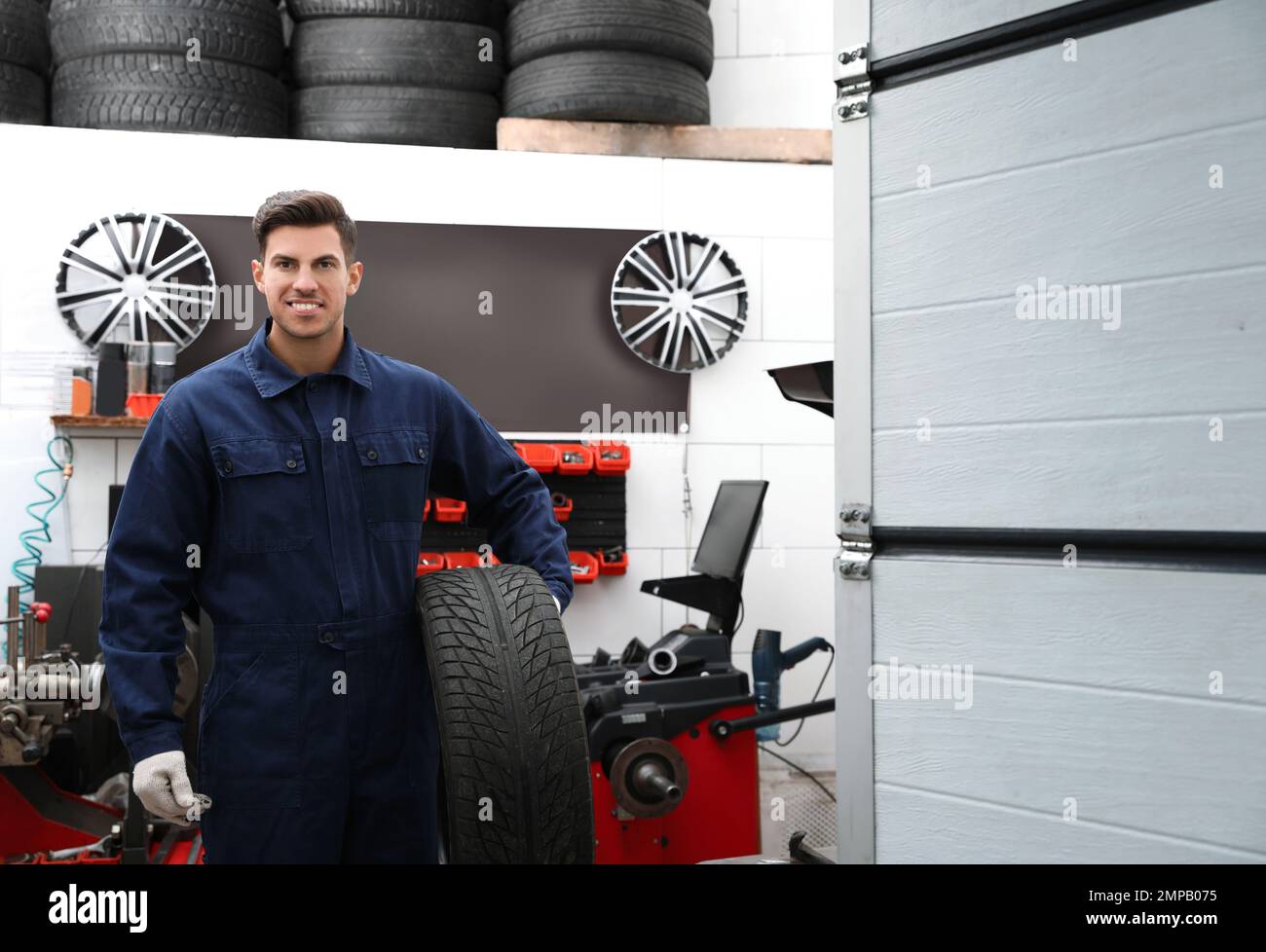 Professional worker with wheel in shop of modern tire service Stock ...