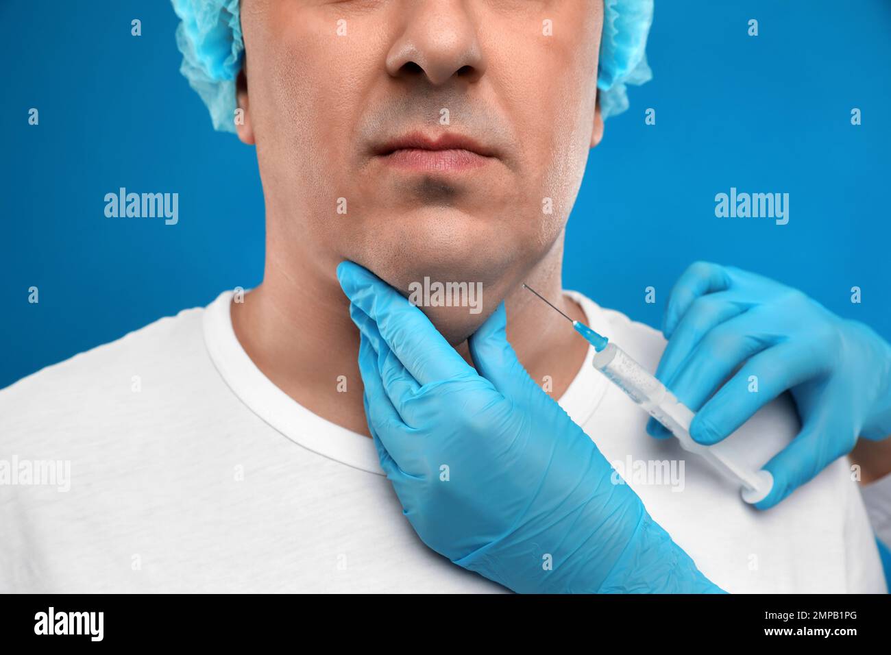 Mature man with double chin receiving injection on blue background ...