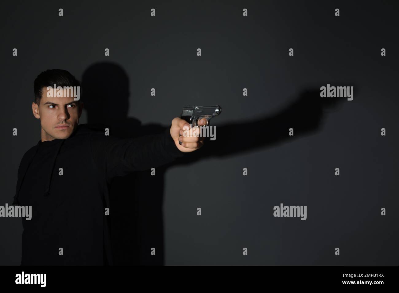 Professional killer with gun on black background Stock Photo - Alamy