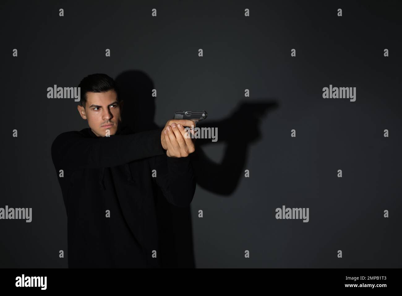 Professional killer with gun on black background Stock Photo - Alamy