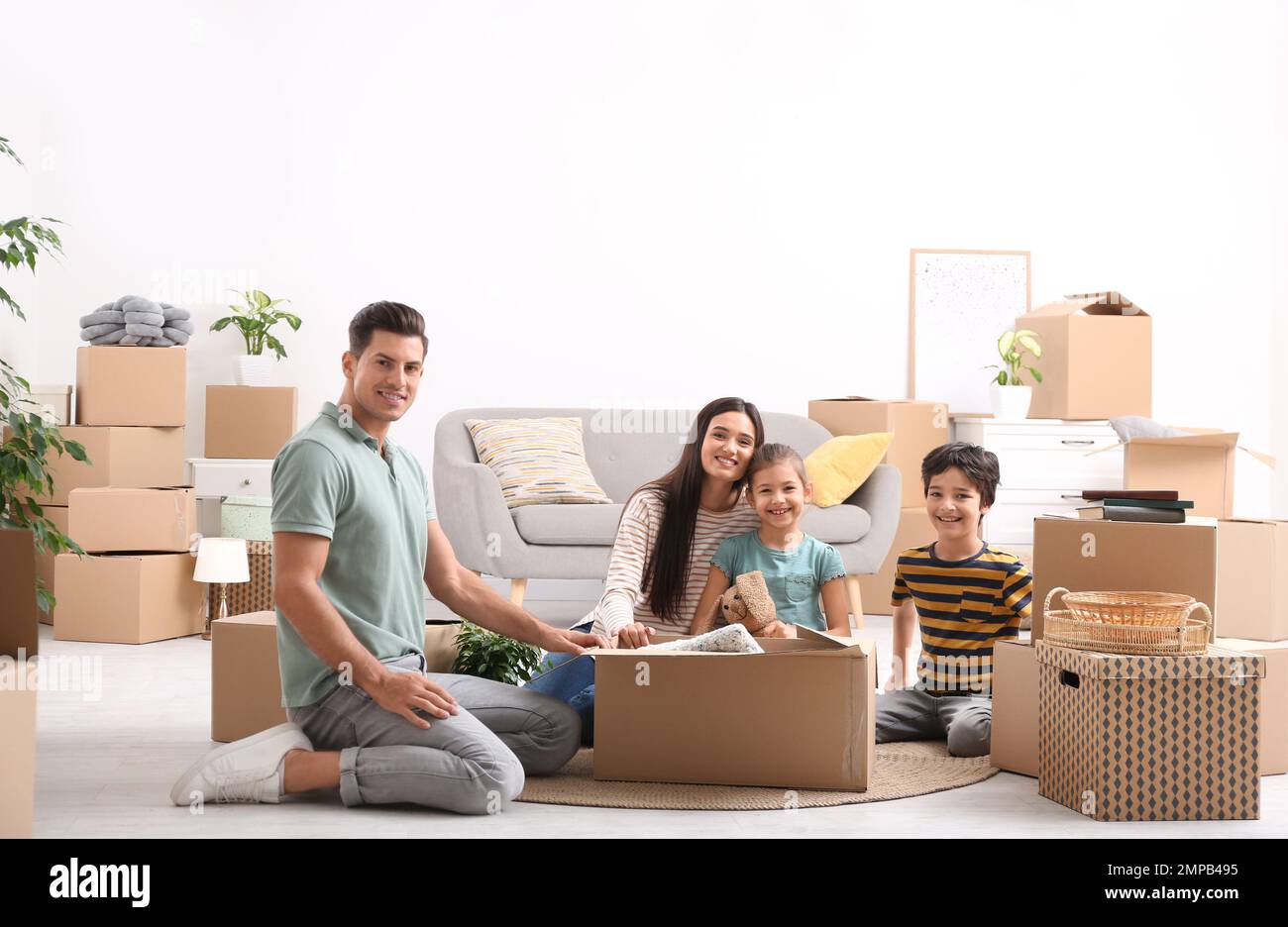 Happy family unpacking moving boxes at their new home Stock Photo - Alamy
