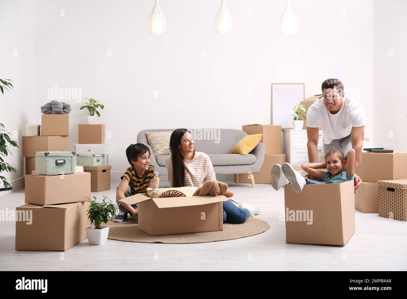 Happy family having fun while unpacking moving boxes at their new home ...