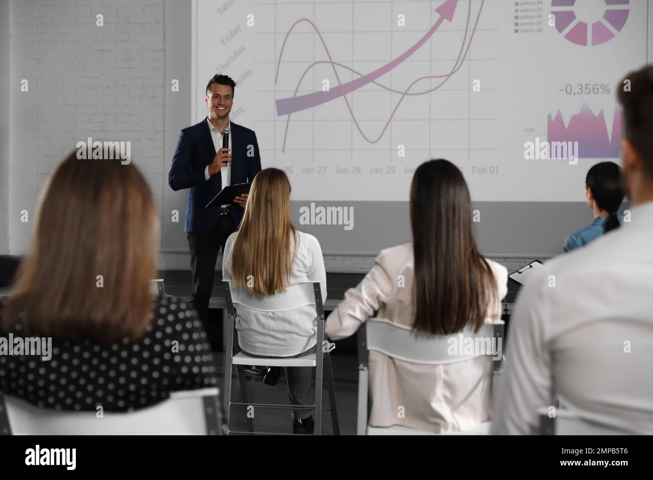 Male business trainer giving lecture in conference room with projection ...