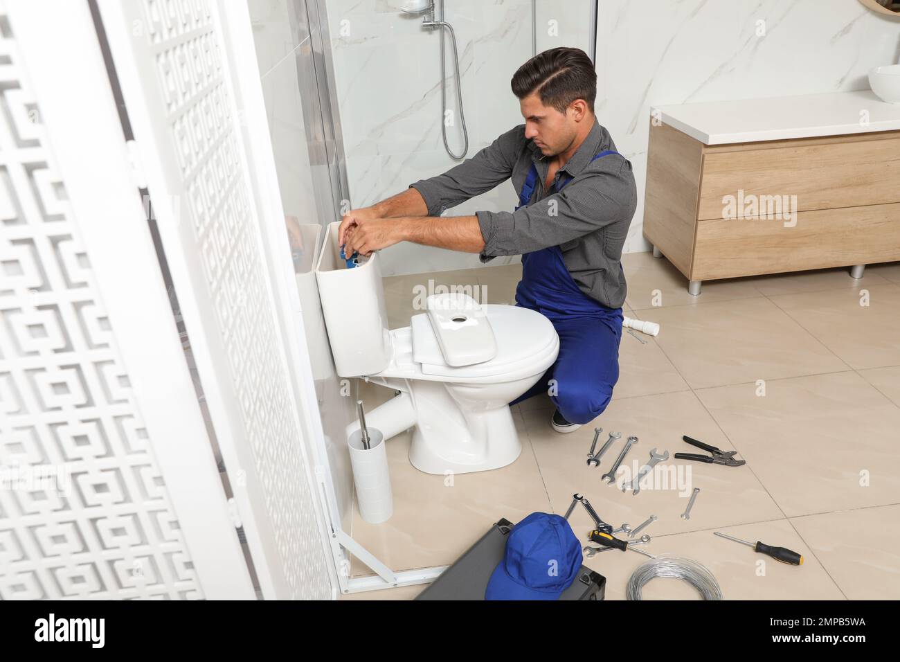 Professional plumber working with toilet bowl in bathroom Stock Photo ...