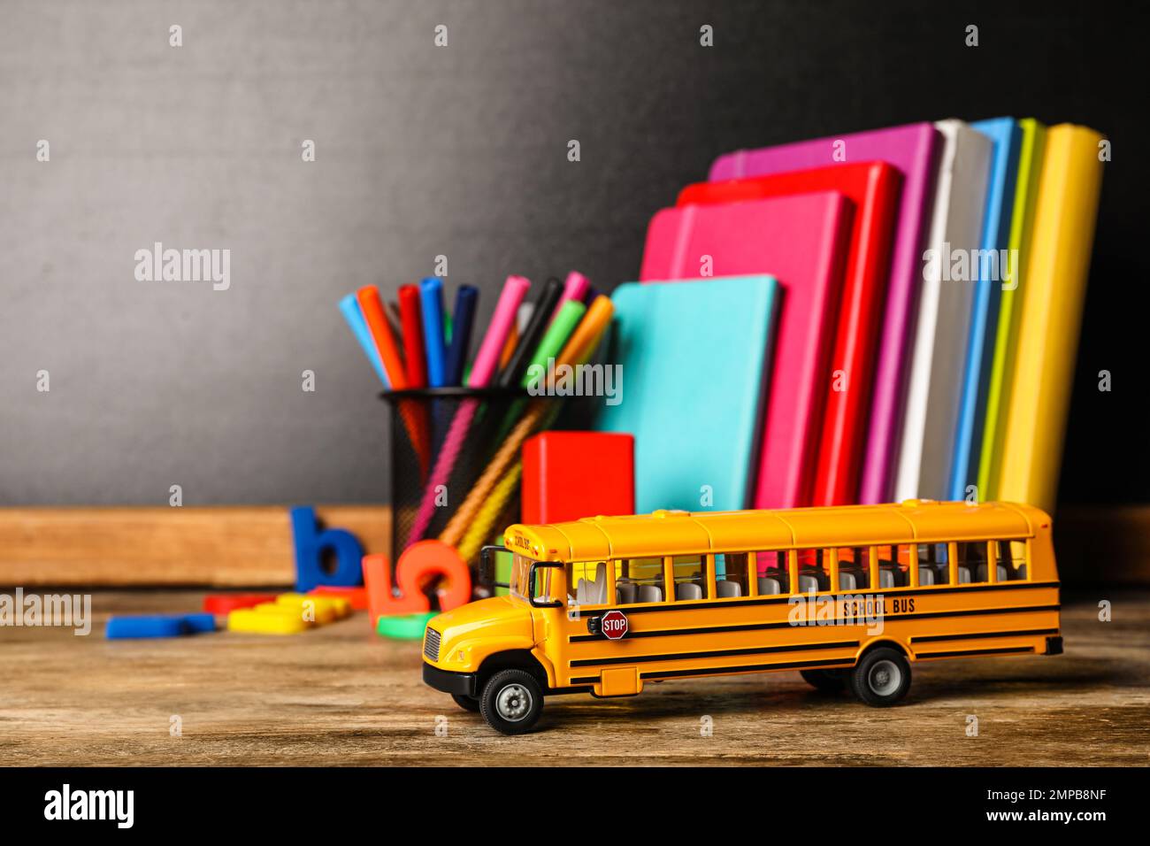 School bus model and stationery on wooden table. Transport for students ...