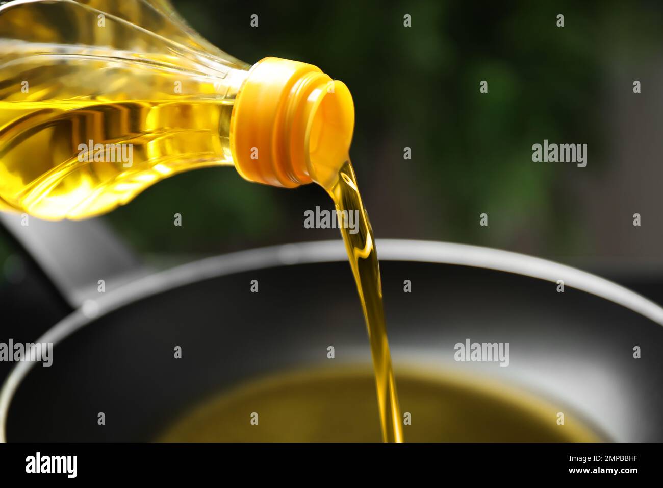 Pouring cooking oil from bottle into frying pan, closeup Stock Photo ...