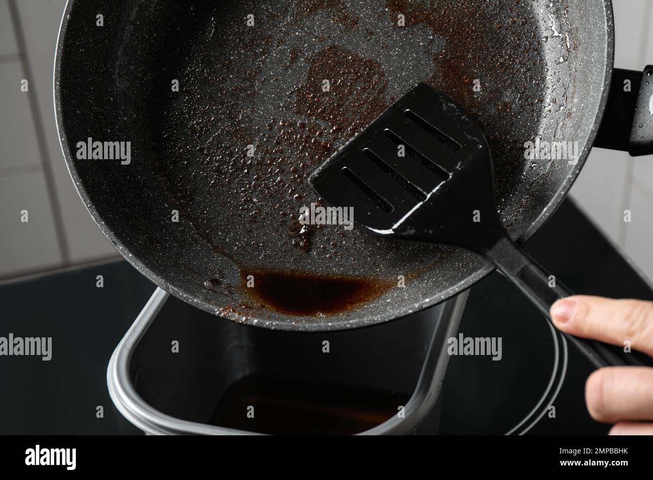 Woman pouring used cooking oil from frying pan into container, closeup ...