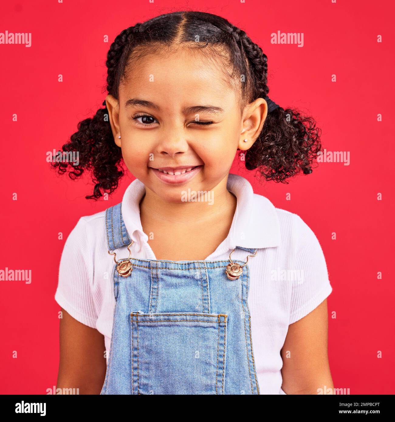 Portrait, wink and a black child on a red background in studio having ...