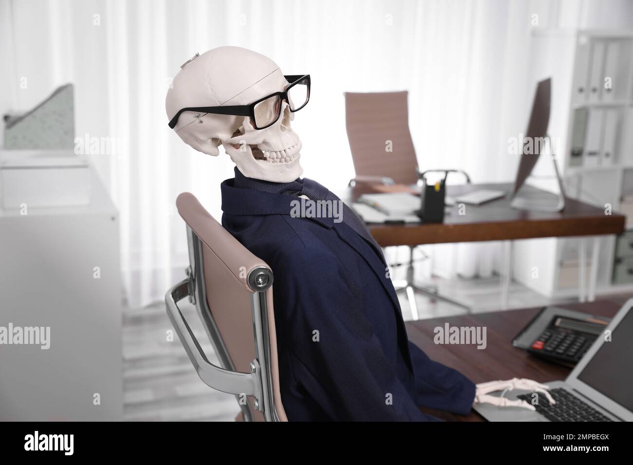 Human skeleton in suit using laptop at table in office Stock Photo - Alamy