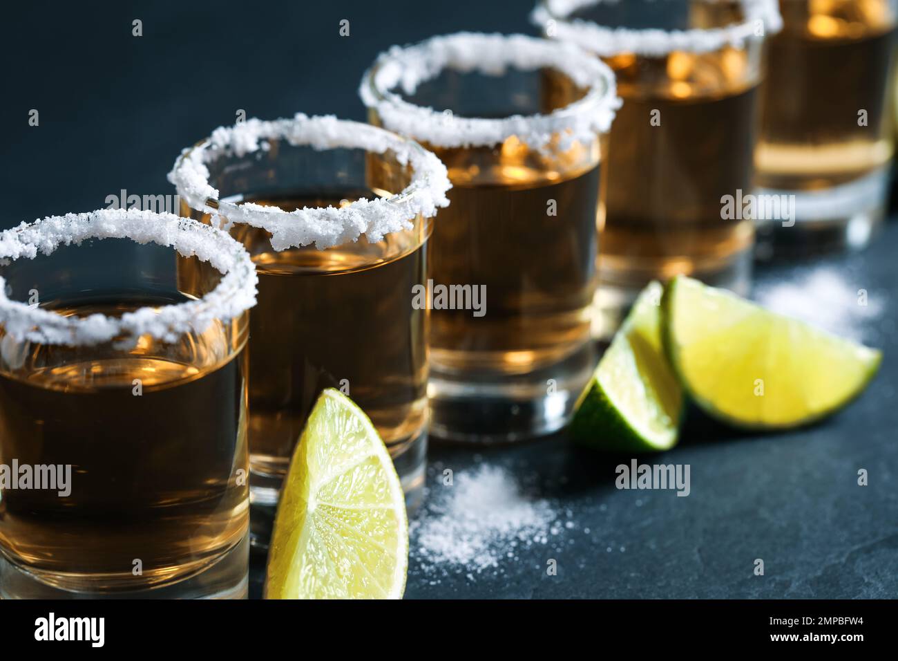 Mexican Tequila shots, lime slices and salt on grey table, closeup ...