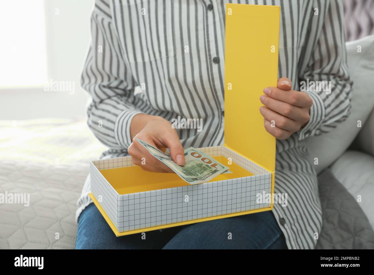 Woman hiding dollar banknotes in box at home, closeup. Money savings ...