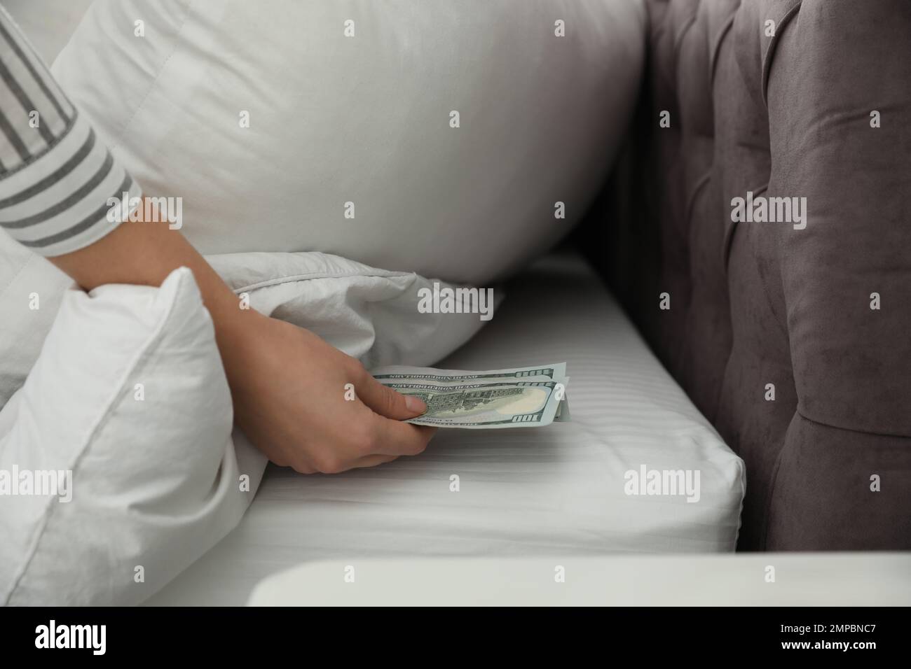 Woman hiding dollar banknotes under pillow in bedroom, closeup. Money ...