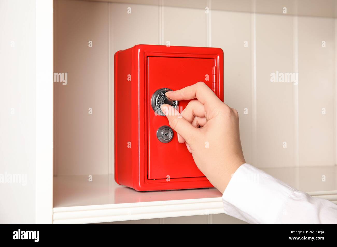 Woman opening red steel safe with mechanical combination lock, closeup ...