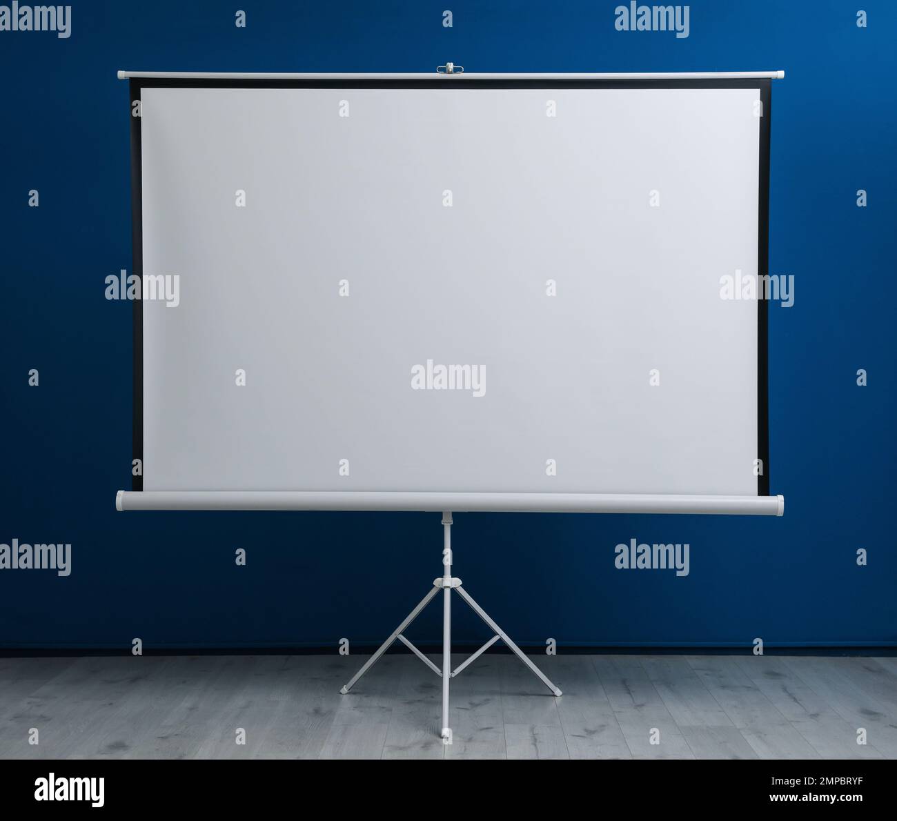 Blank projection screen near blue wall indoors. Space for design Stock ...